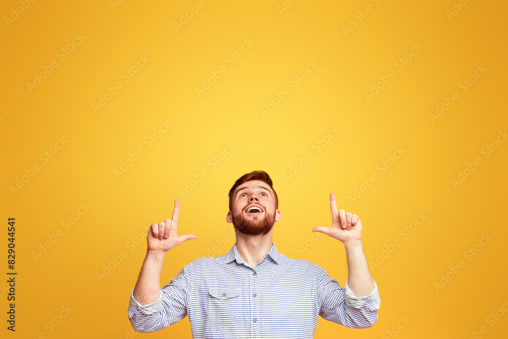 A man standing with hands in the air in front of a bright yellow ...