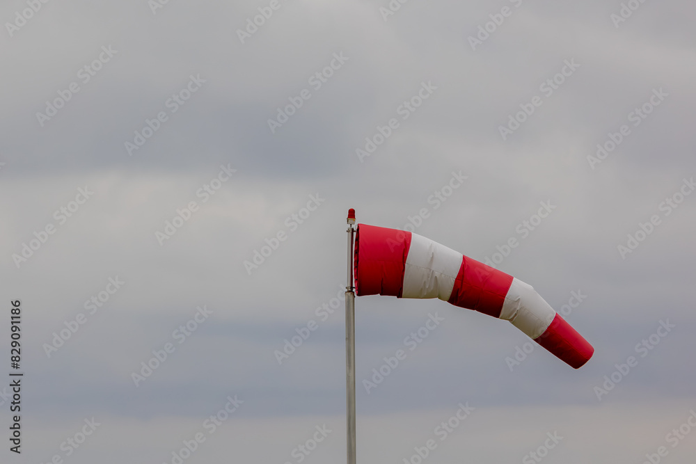 Selective focus of red and white windsock with cloudy sky and storm ...