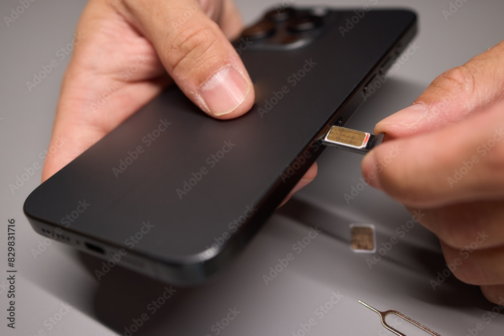 A person is inserting a sim card into a cell phone using hand and ...