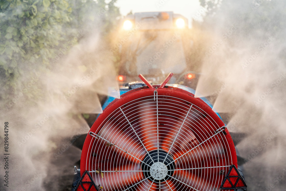 Tractor with agricultural sprayer machine with big fan spraying orchard ...