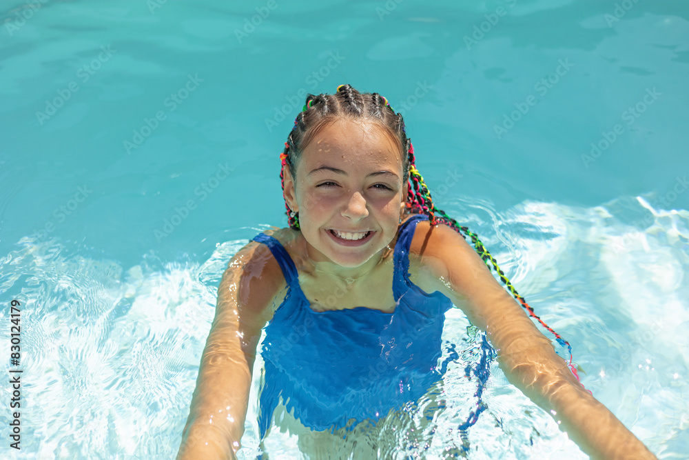 Laughing little girl with colorful braids in her hair standing in the ...
