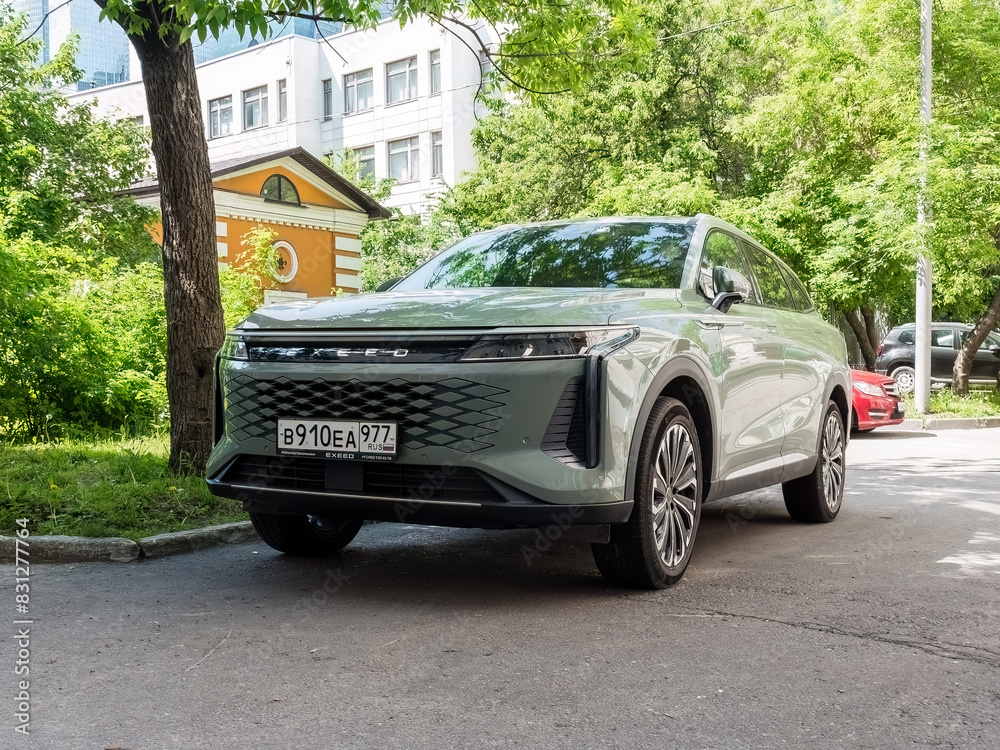 Green car EXEED RX, front side view against the background of house ...
