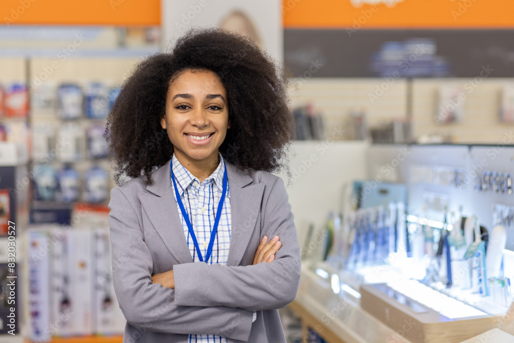 Confident female retail employee with curly hair, smiling and standing ...