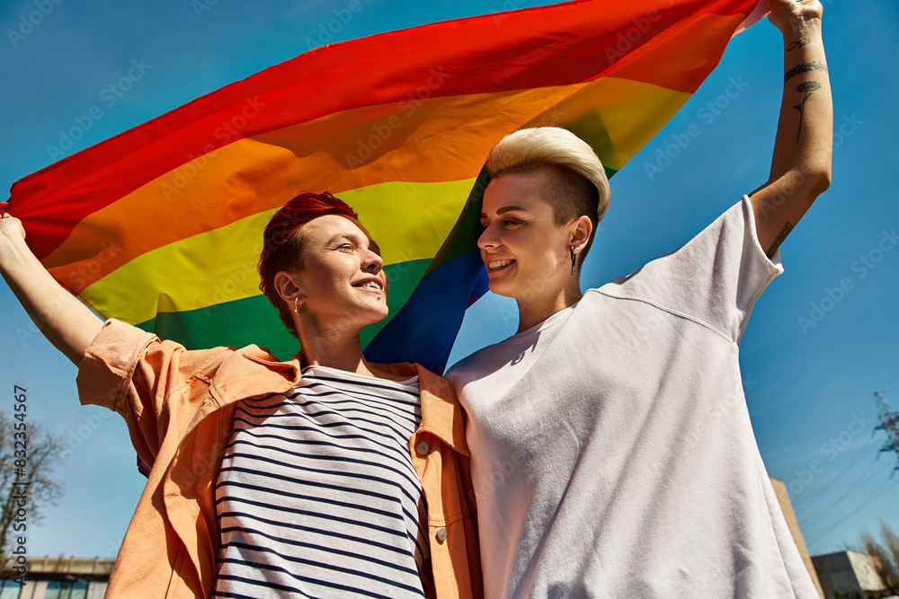 Two young women proudly hold up a rainbow flag in solidarity with the ...