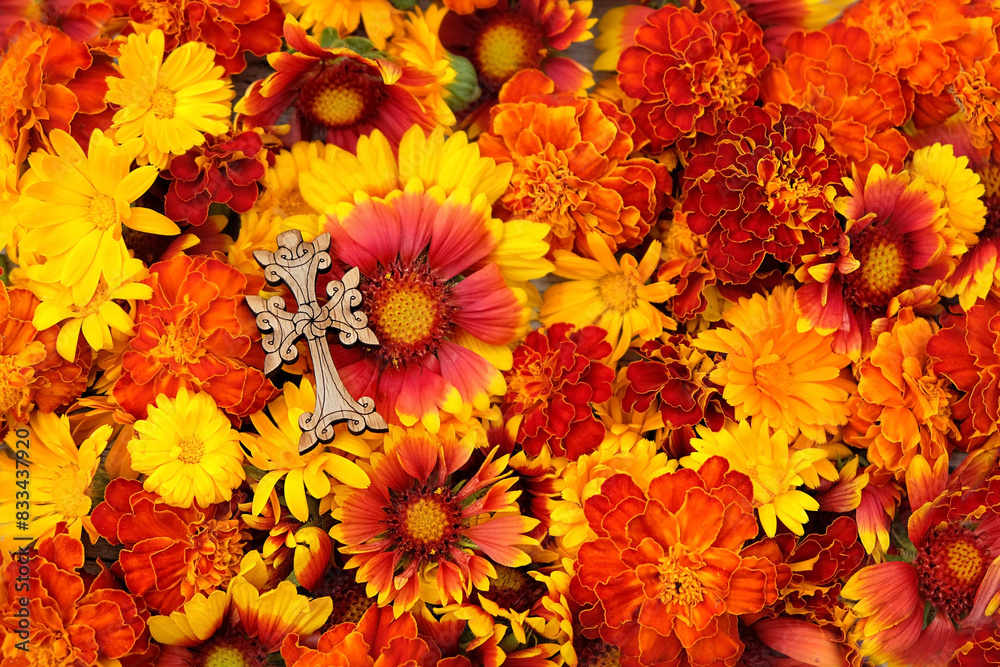 orange-red colorful flowers and wooden christian cross on table. Symbol ...