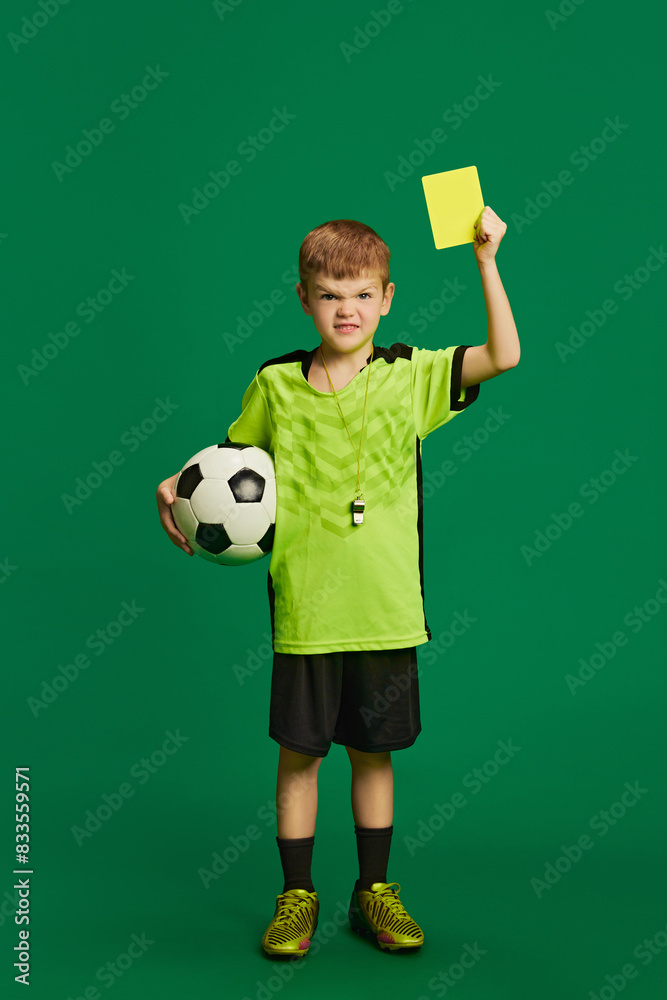 Boy dressed as soccer referee holding ball and yellow card with angry ...