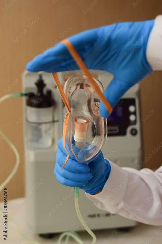 Hands in medical gloves hold out an oxygen mask against the background ...