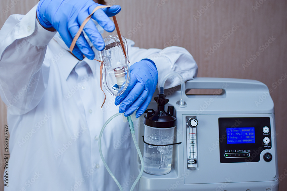 Hands in medical gloves hold out an oxygen mask against the background ...