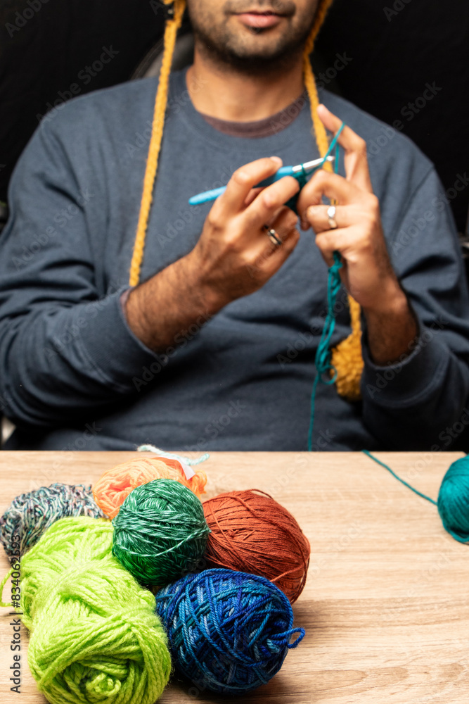 Hombre tejiendo a palillos con lanas de colores Stock Photo | Adobe Stock