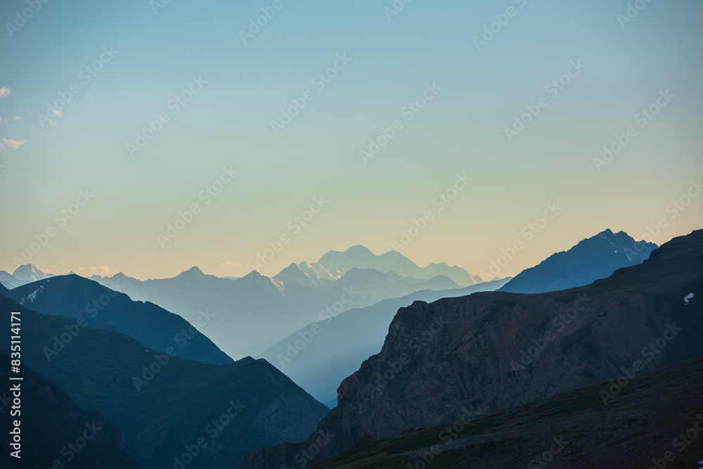 Deep gorge between layered silhouettes of sharp rocky ridge spurs under ...