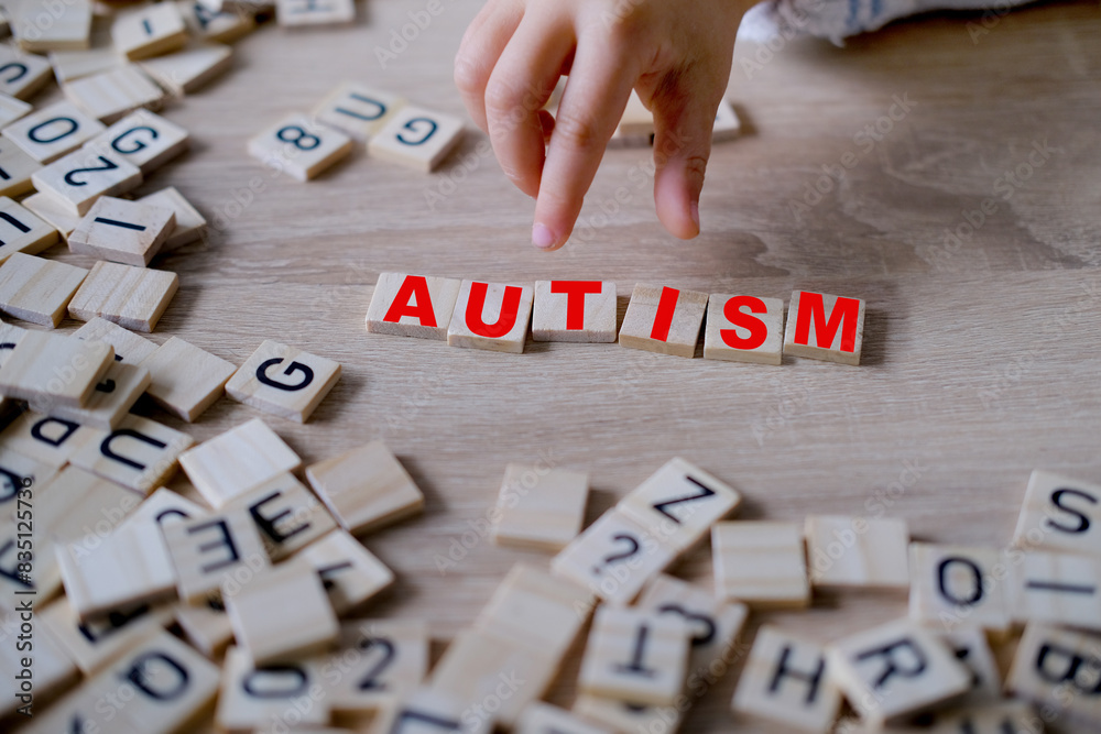 child's hand complete word "AUTISM," symbolizing importance of early ...