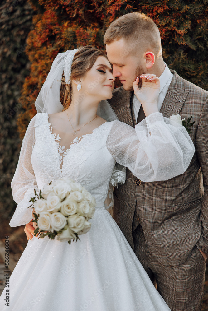 A bride and groom are hugging and kissing each other. The bride is ...