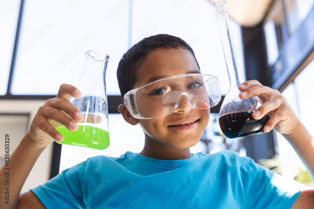 Biracial boy conducts a science experiment at school in the classroom ...