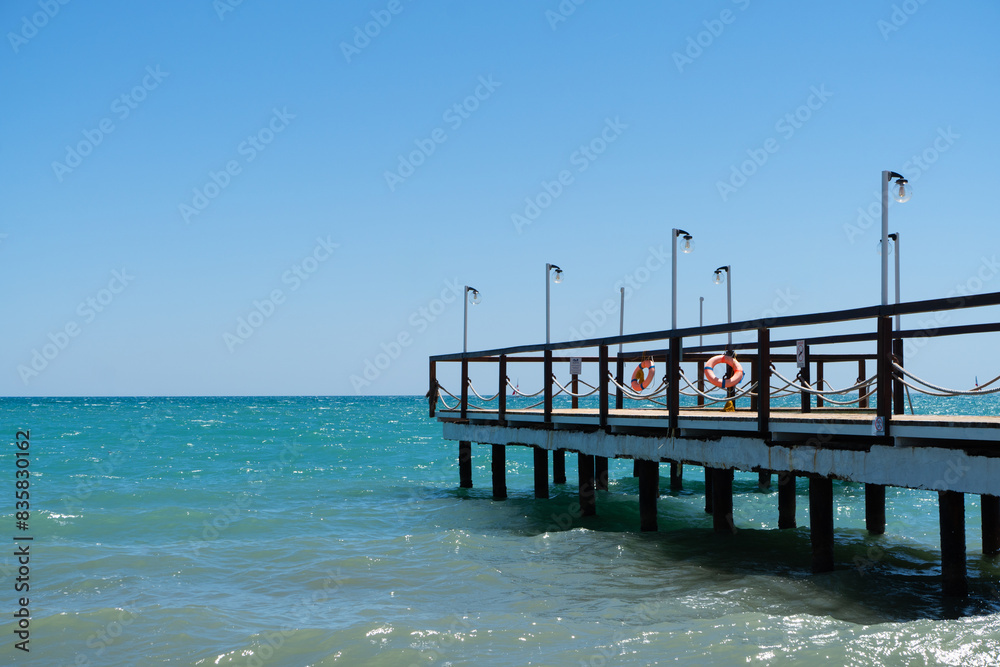 Old pier with posts and ropes with sparkling sea water. Pier with blue ...
