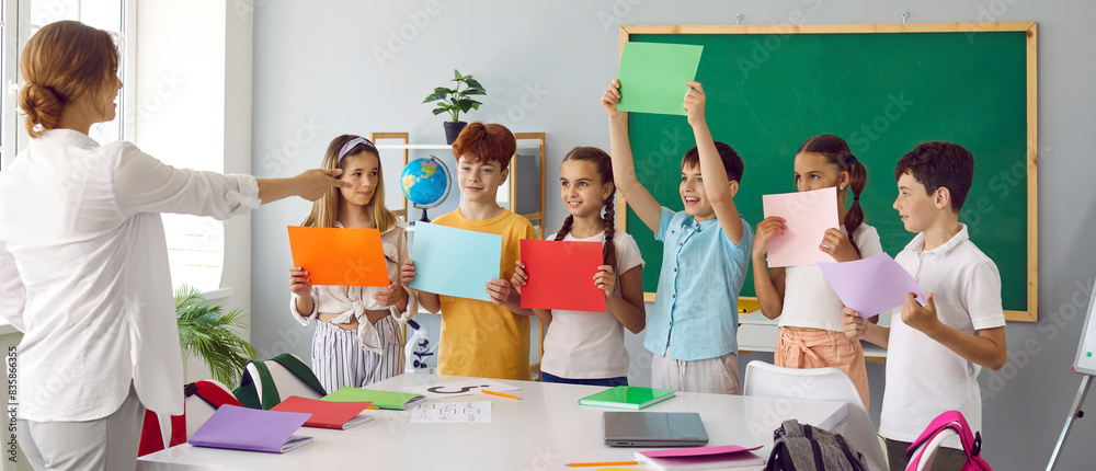 Elementary school students showing blank paper sheets to teacher in ...