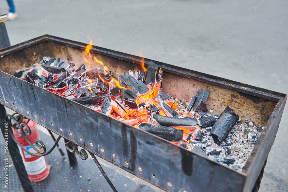 Fire and smoldering coals inside a metal grill for frying meat or ...