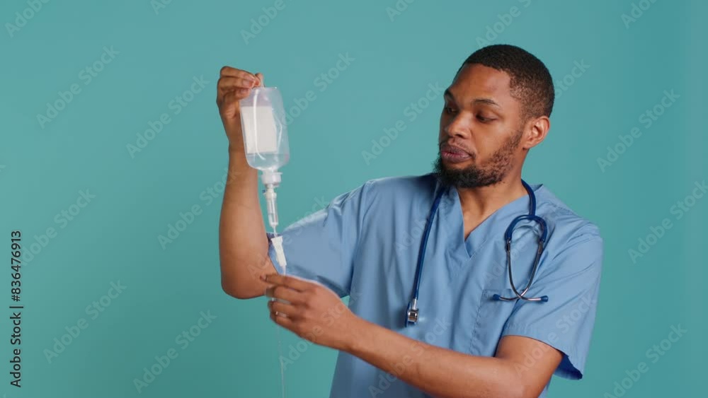 Male nurse holding IV bag, preparing to use it to administer fluids ...