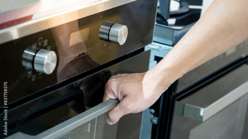 Male hand holding handle bar opening electric oven door in kitchen ...
