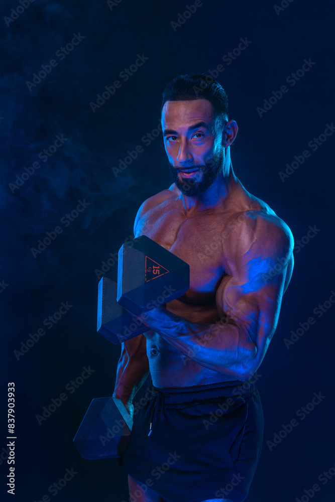 Bodybuilder with dumbbells in neon colors. Athlete man posing on black ...