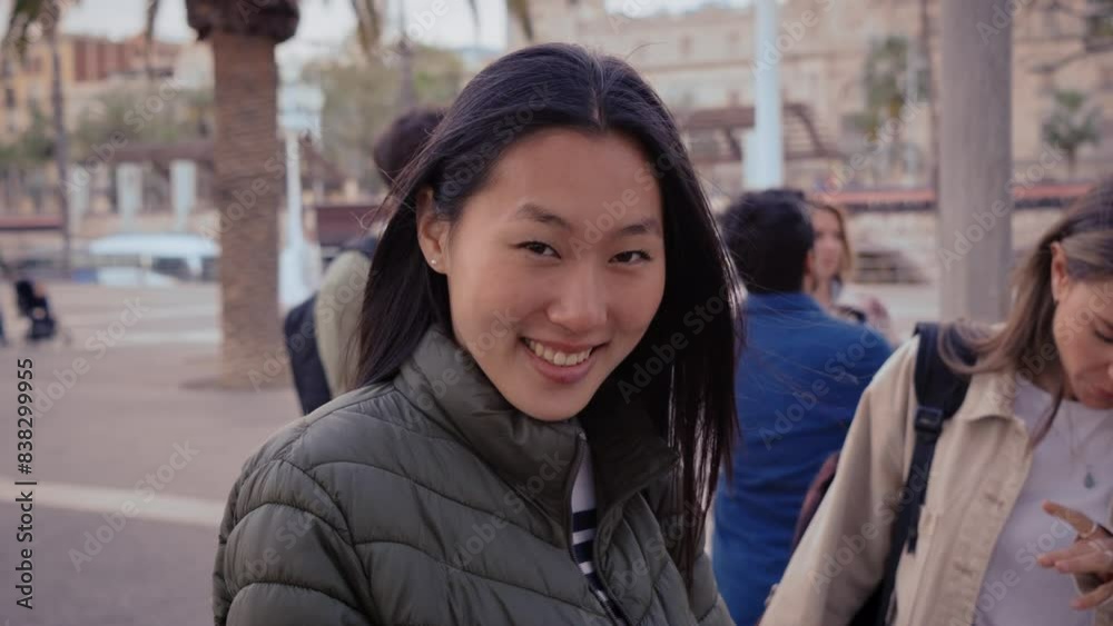 Young Asian woman looking at smiling camera with university friends ...