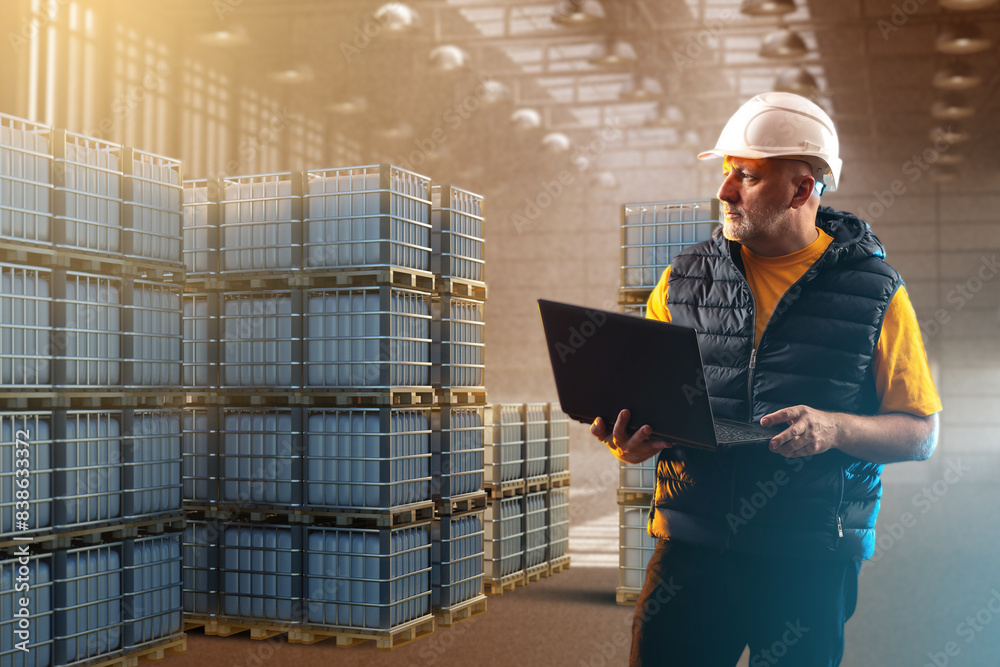 Man in chemical warehouse. Guy with laptop near plastic tanks. Manager of chemical manufacturing ...