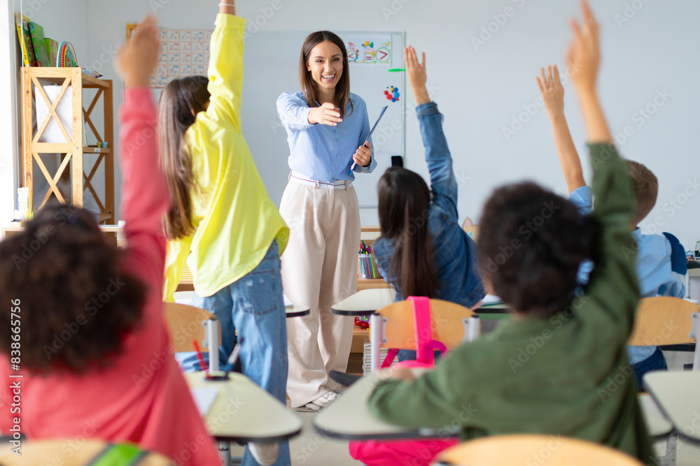 Students raising their hands up in classroom at international ...