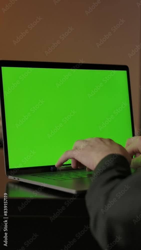 Man typing on laptop keyboard with green screen, dolly out smooth ...