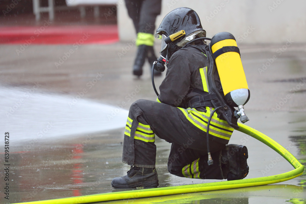 Firefighter kneeling to avoid flames with oxygen cylinder and ...