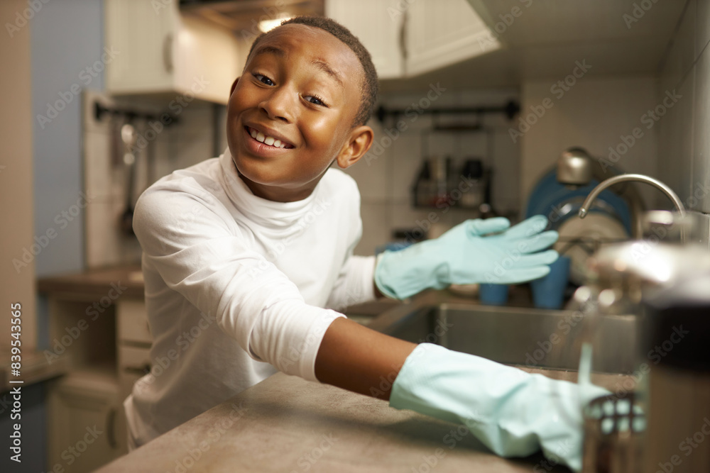 Happy black teen boy in blue rubber gloves rubbing counter and showing ...