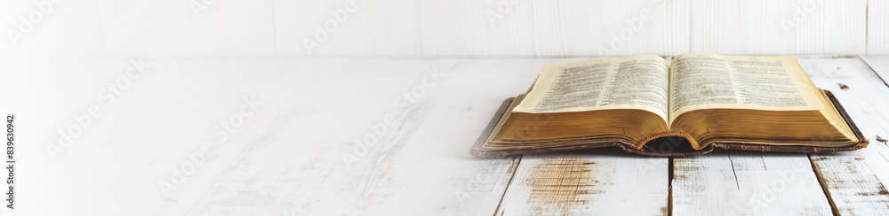 Open holy bible on a white wooden surface. With extra wide copy space ...