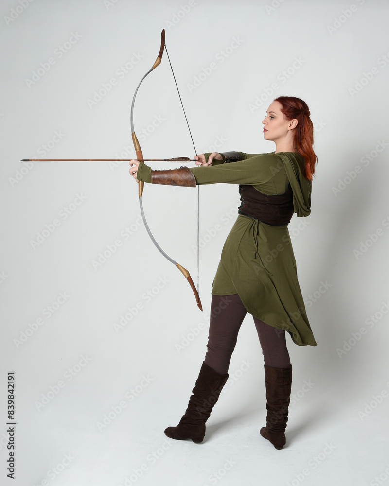 Full length portrait of red haired female model wearing green medieval ...
