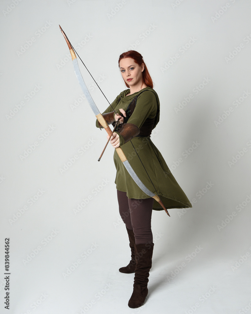Full length portrait of red haired female model wearing green medieval ...