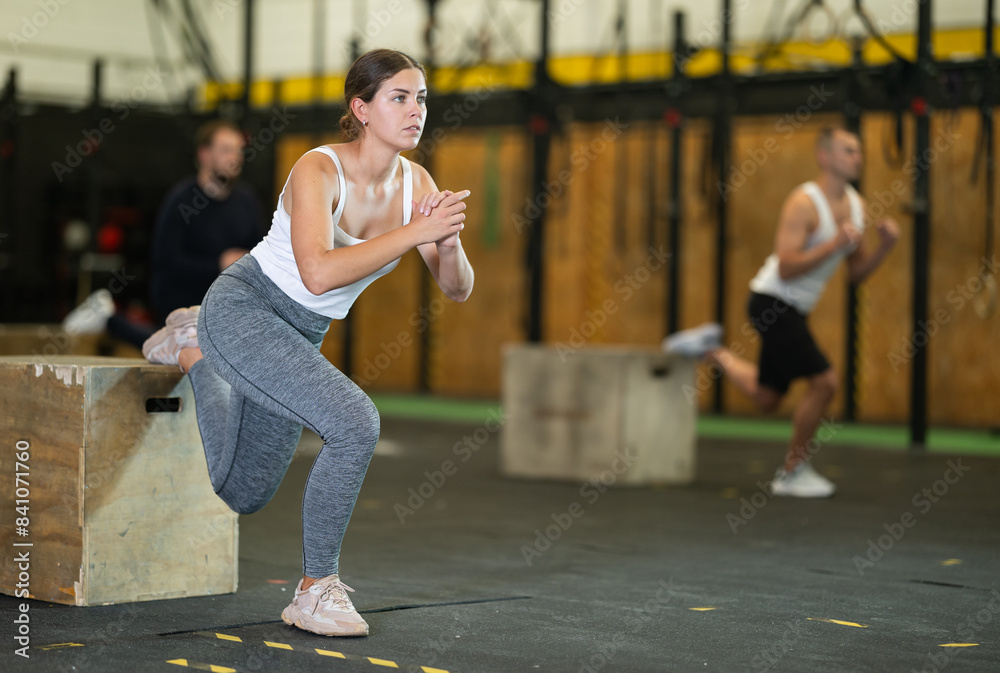 Motivated young girl performing Bulgarian split squats using wooden ...