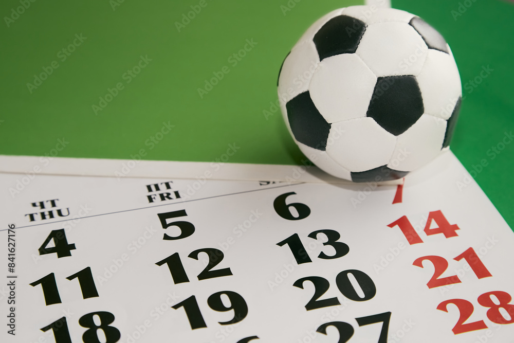 Soccer ball lies on a green background and calendar with date 14th ...