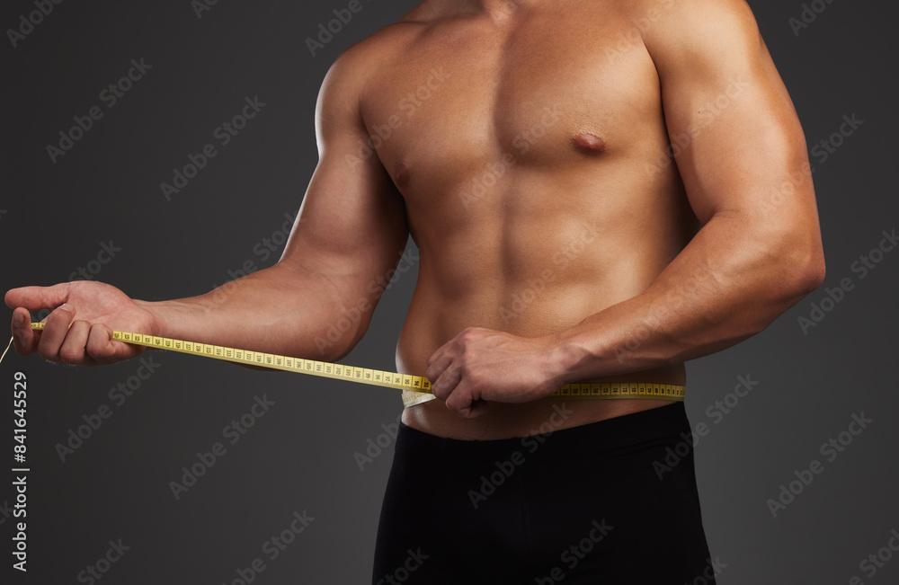 Stomach, body and fitness man in studio with measuring tape for ...
