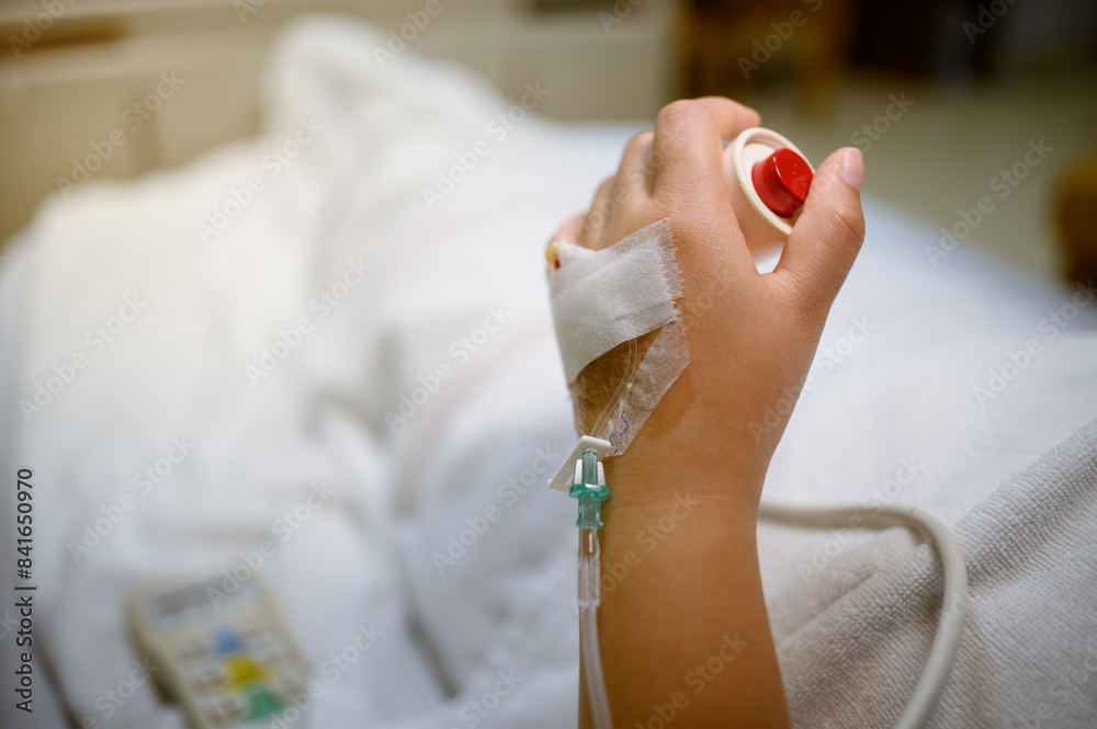 Patient's hand on hospital bed An intravenous (IV) line is inserted and ...
