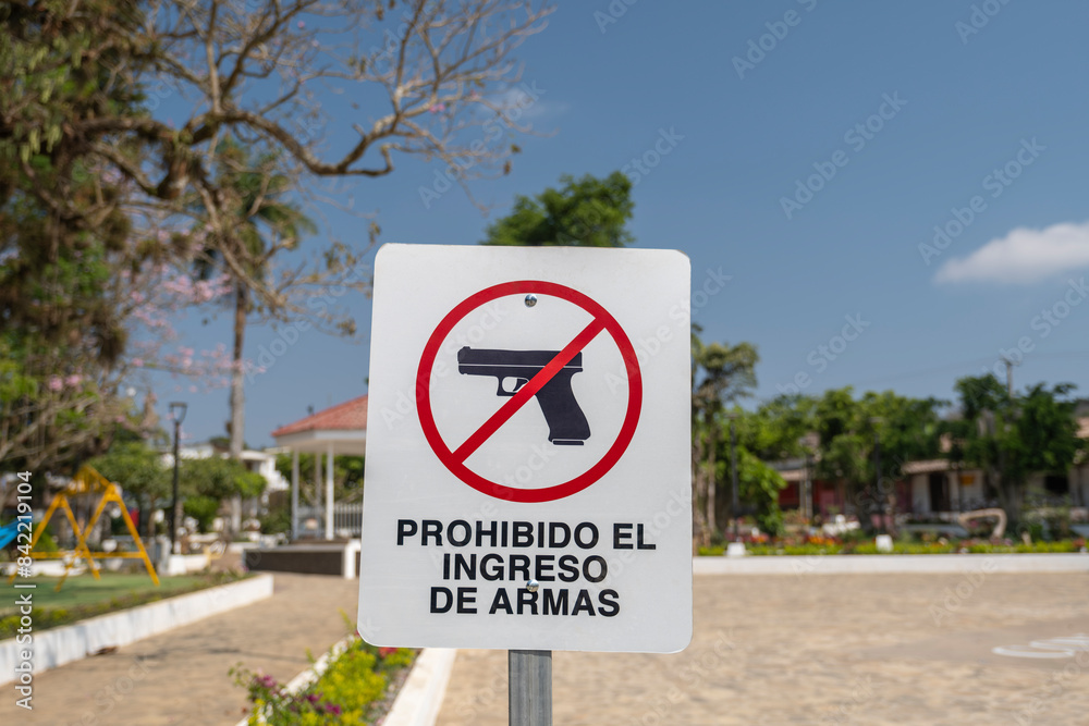 Sign with crossed hand gun and sign in Spanish entry with weapons ...