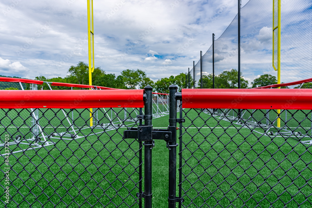 Black chain link fence, gate, with red fence cap and softball ...