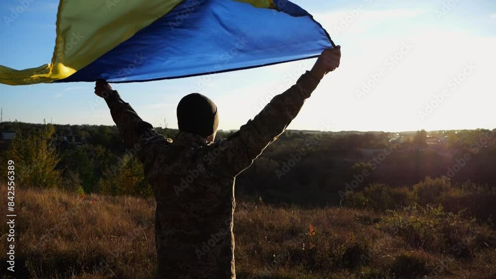 Military man in uniform stands with raised over head Ukraine flag ...