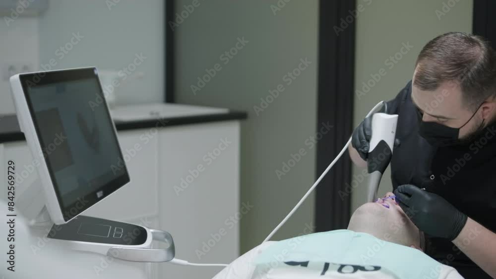 Doctor scans the patient's teeth in the clinic. The dentist holds in ...