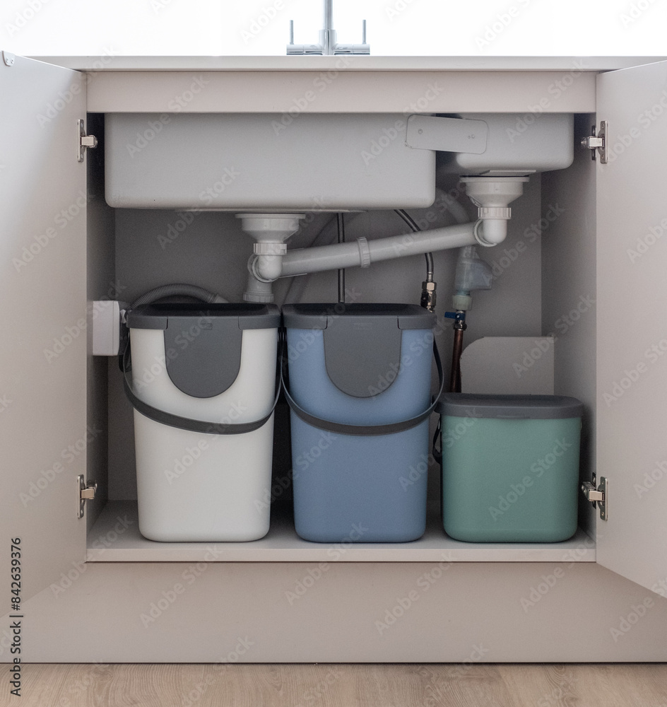 Colourful domestic recycling bins, kept in a kitchen cupboard under the ...