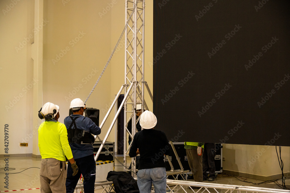 Three technical workers dressed in safety clothing work assembling an ...
