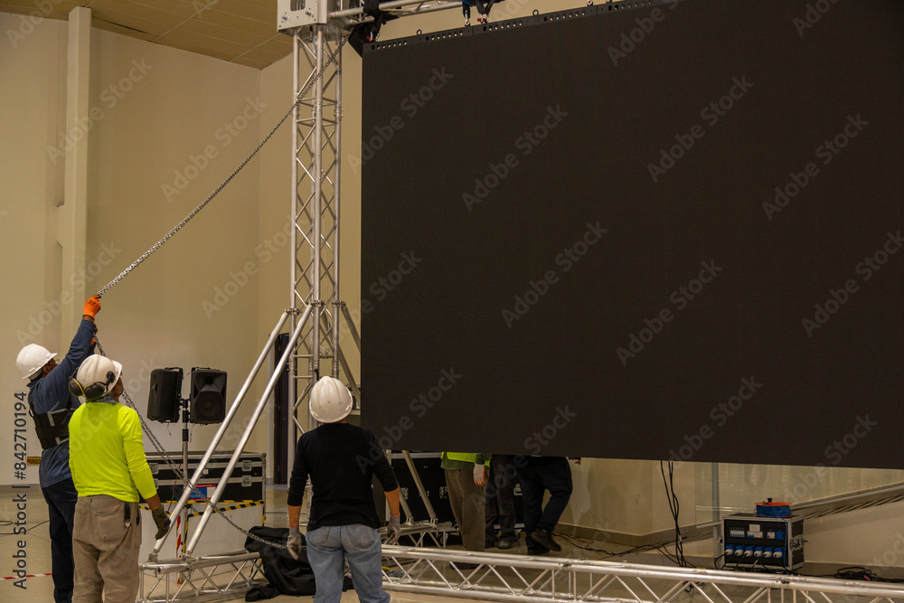 Three technical workers dressed in safety clothing work assembling an ...