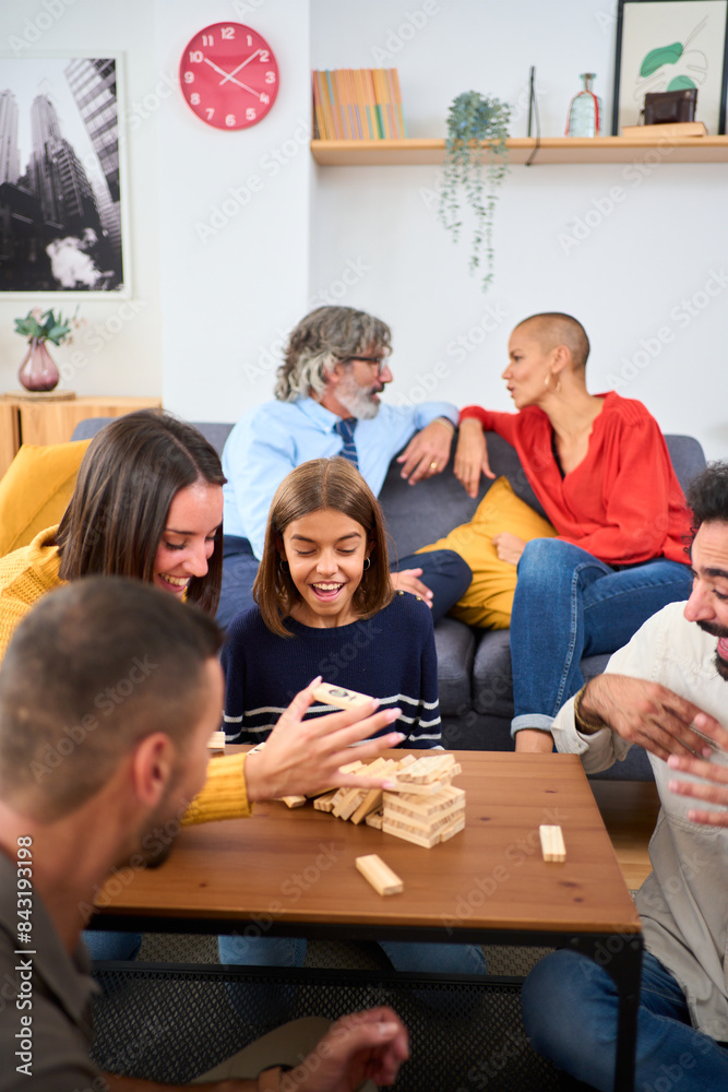 Vertical. Excited multi-generational family gathering playing Jenga at ...