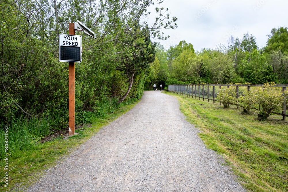 Digital LED Your Speed sign, aimed at bike riders, on a wide gravel ...