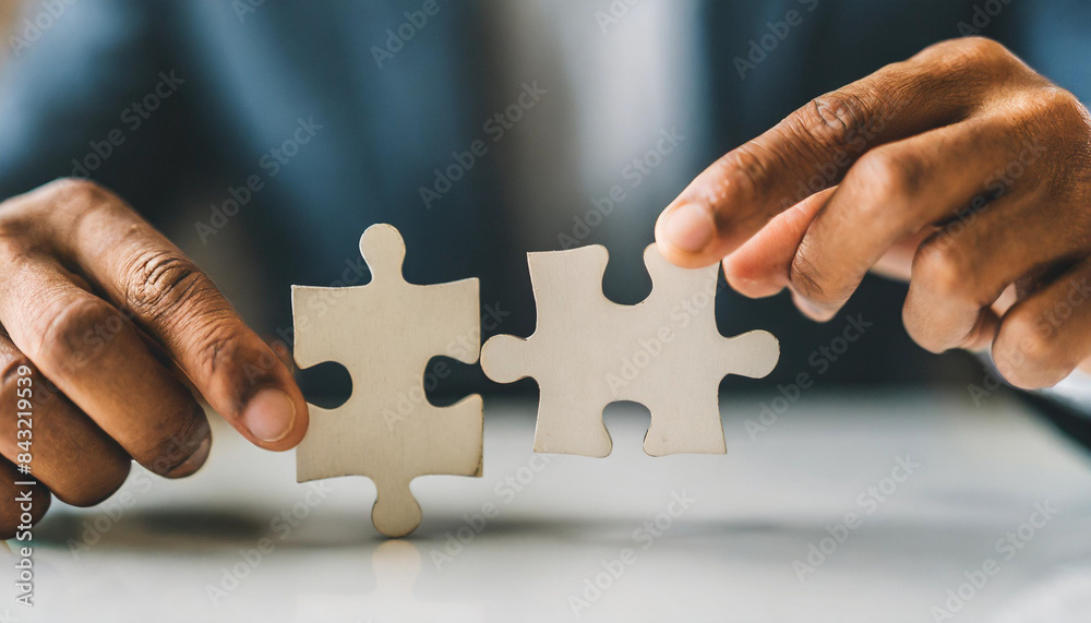 Two hands each holding a jigsaw puzzle piece, aligning them against a ...