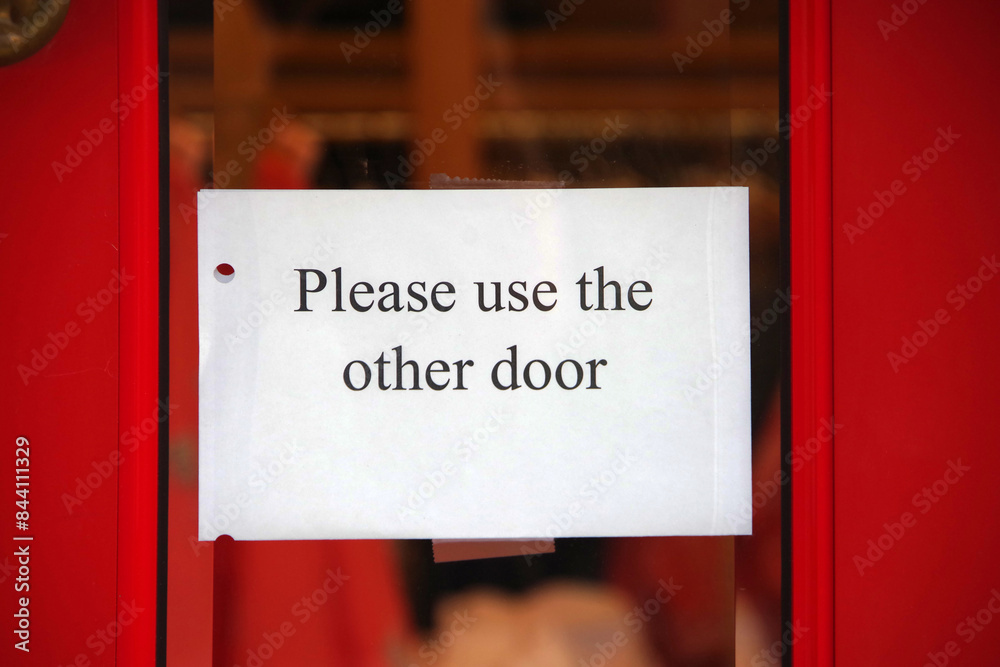 PLEASE USE THE OTHER DOOR sign taped onto a restaurant glass door Stock ...