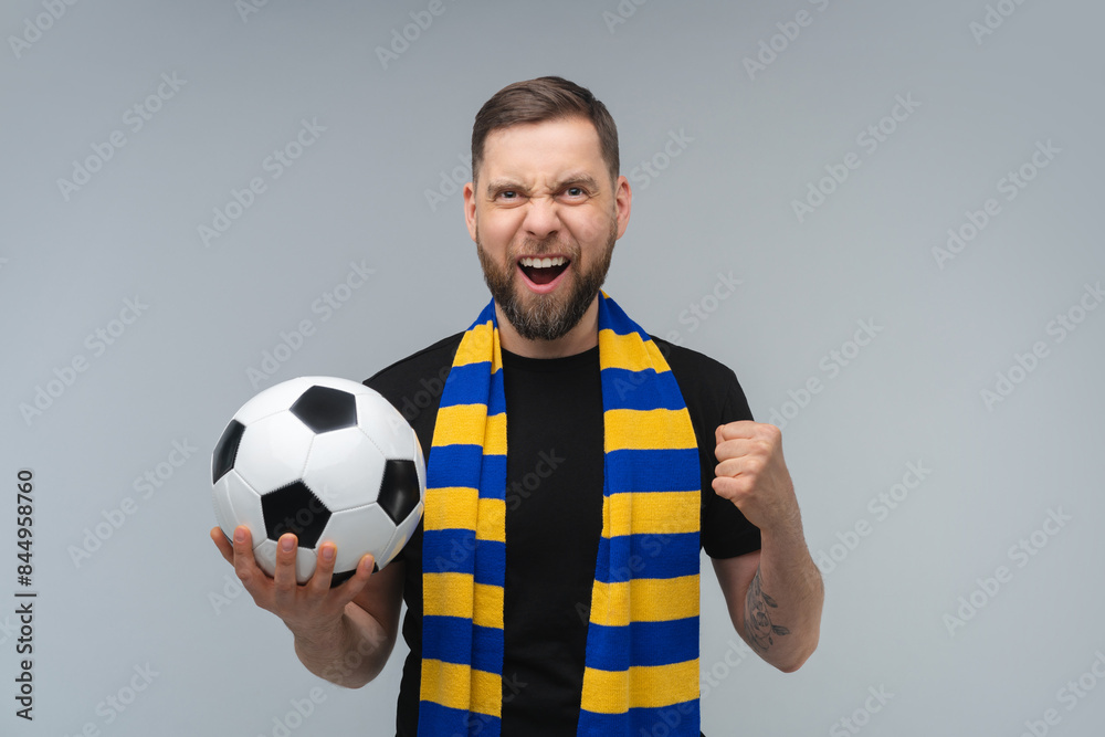 Studio portrait of happy excited soccer fan man wearing yellow-blue ...