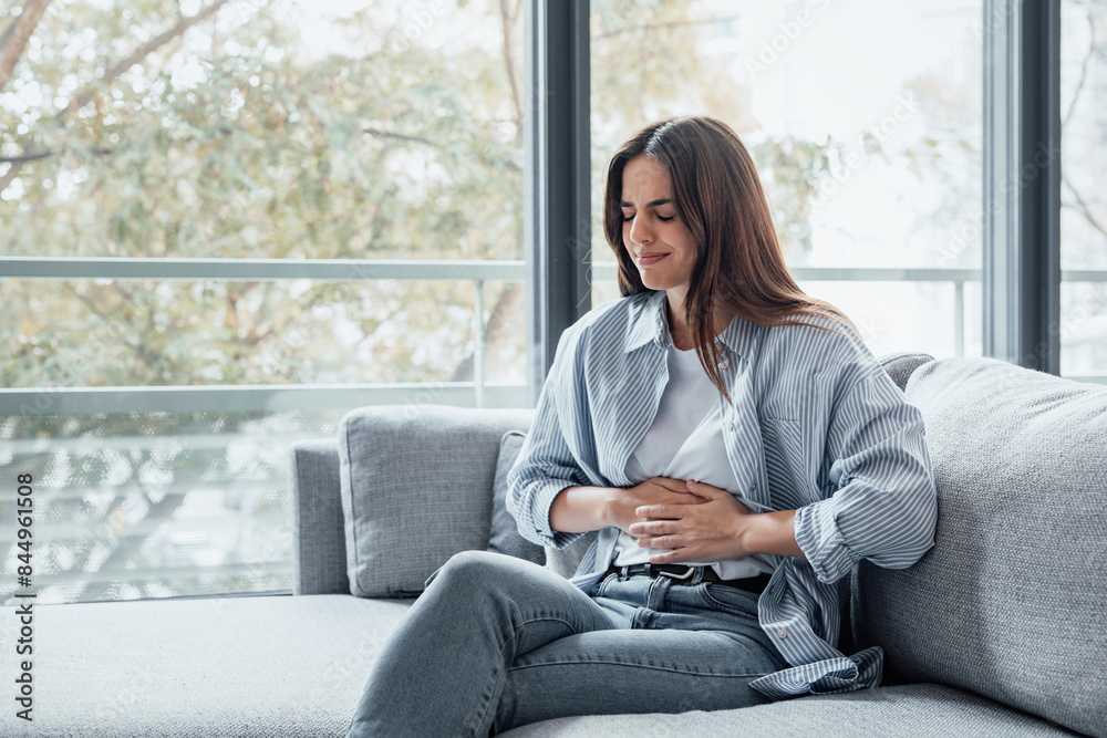 Sick young woman in pain holding belly stomach feeling hurt abdomen ...