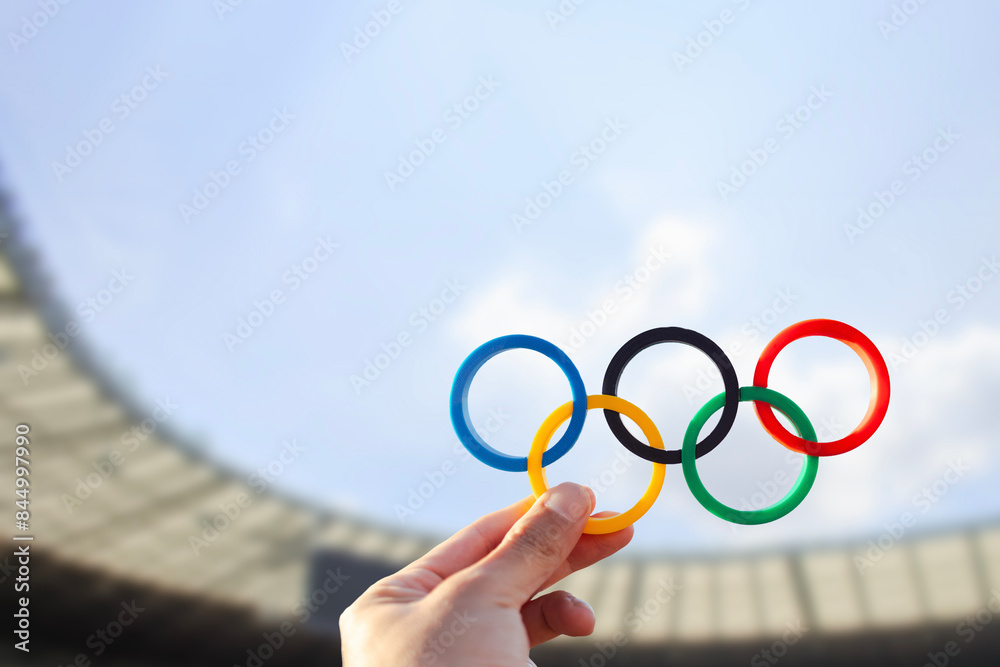 A hand holds the Olympic rings with colors representing the continents ...